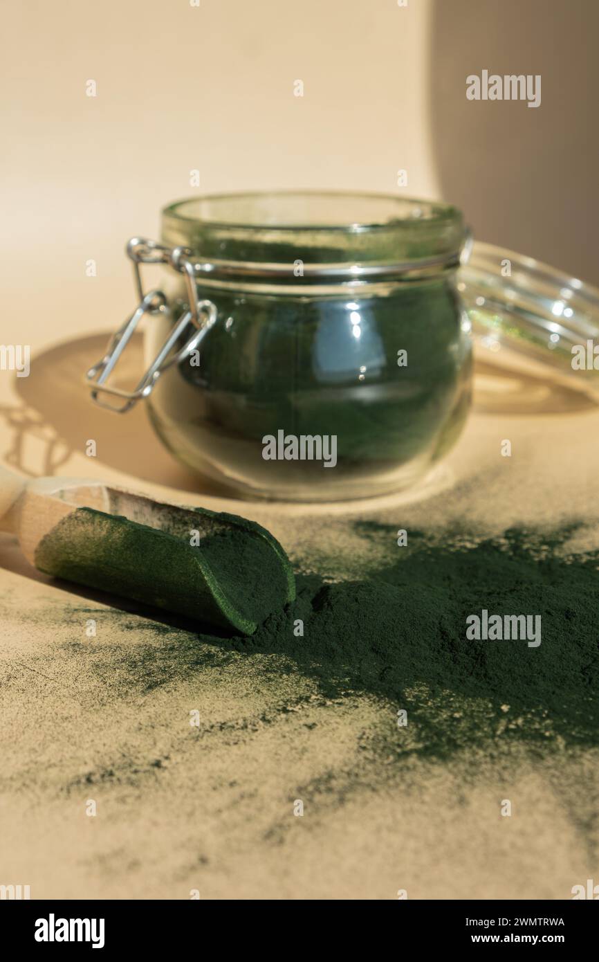 Organic blue-green algae spirulina powder food in glass jar with wooden ...