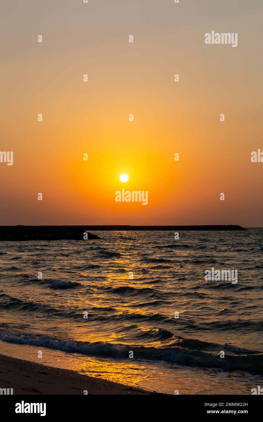 Orange sunset with golden reflections in sea waves and silhouettes of ...