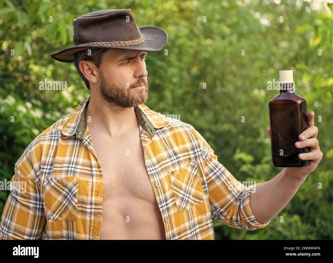 cowboy man showing whiskey bottle. cowboy man with whiskey outdoor ...