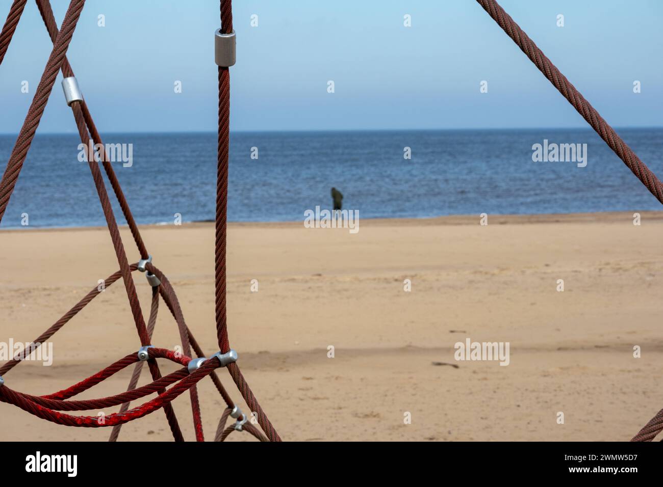 Red rope sections fastened with a metal clamp on a background of brown ...