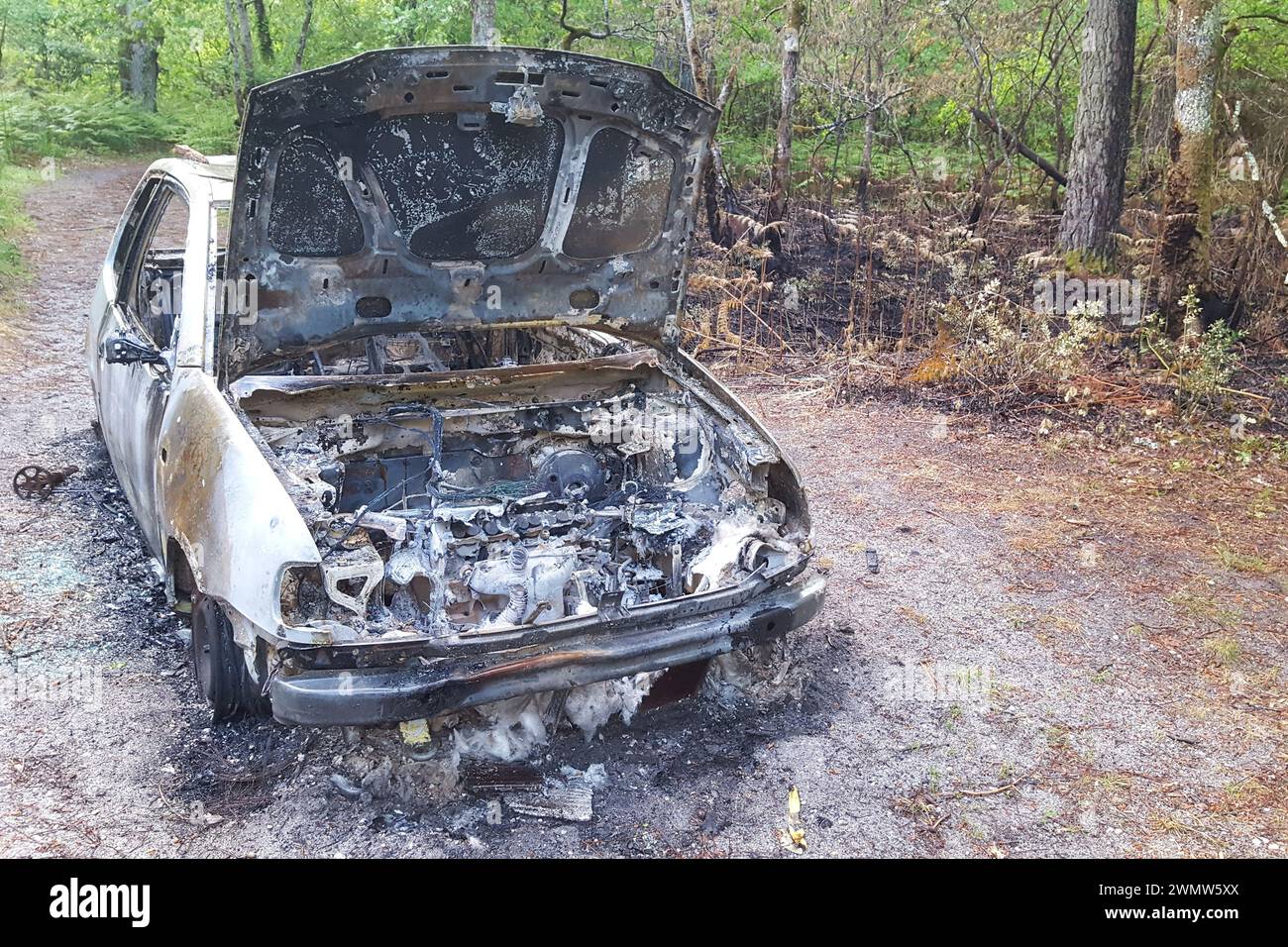 Front and side view of abandoned burned out car left on side of the ...