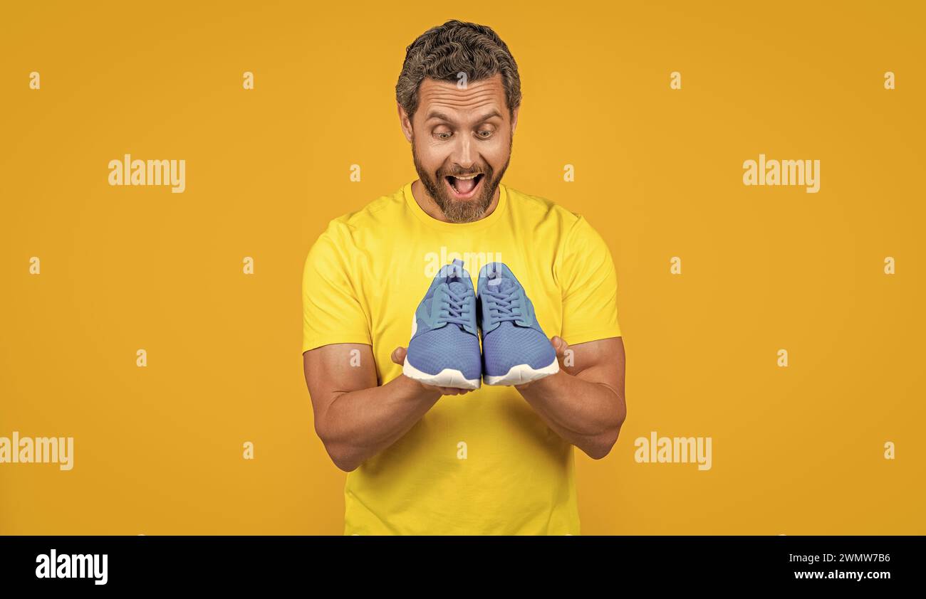shocked fitness man with sneakers isolated on yellow. fitness man with ...