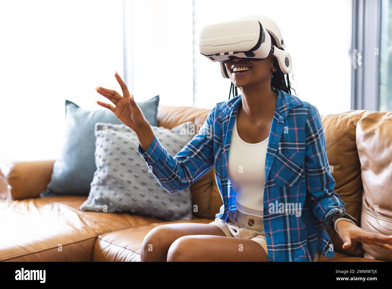 Young African American woman enjoys a virtual reality headset, seated ...