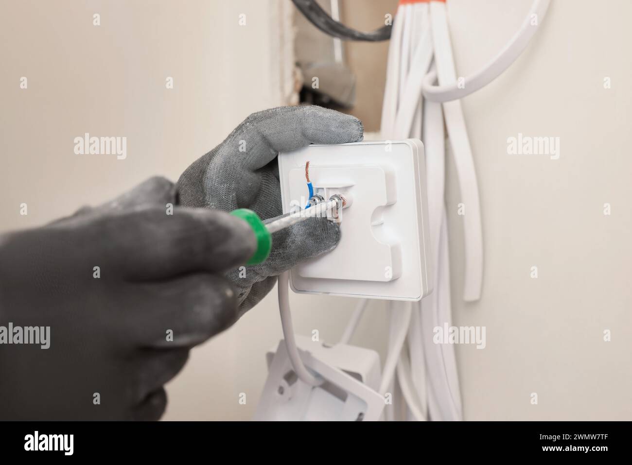 Electrician installing remote meter with screwdriver indoors, closeup ...