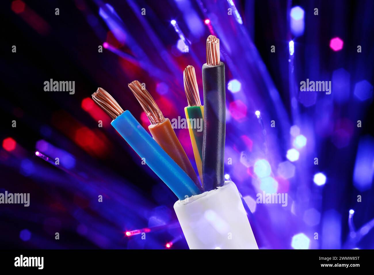Colorful electrical wires against dark background with blurred lights ...