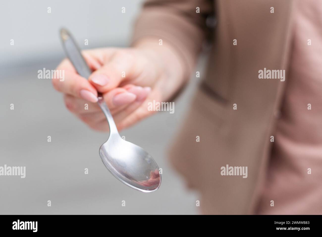 Metallic empty eating spoon in a human right hand with clipping path ...