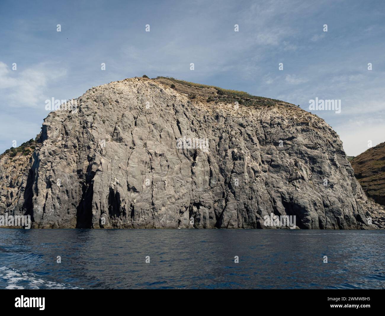 Weathered seaside rock face texture with parts of green and blue water ...