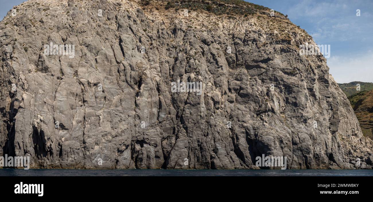 Weathered seaside rock face texture with parts of green and blue water ...