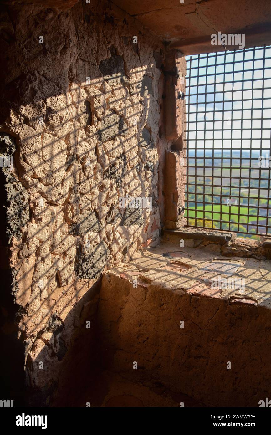 Sun shines through an old castle window with bars with shadows on the ...