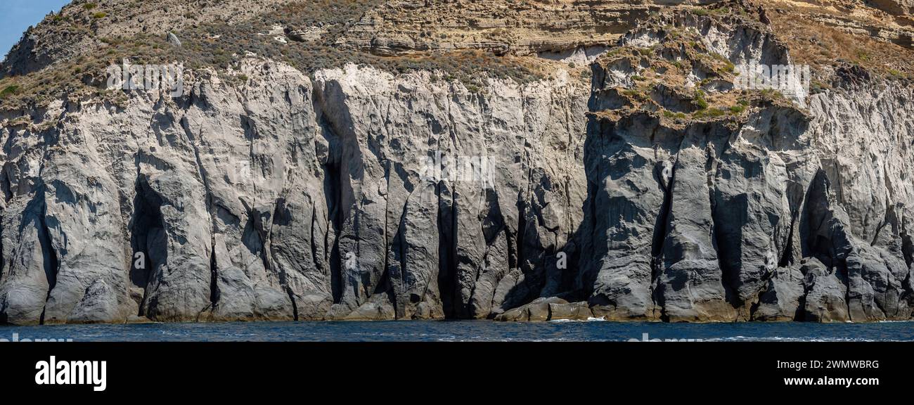 Weathered seaside rock face texture with parts of green and blue water ...