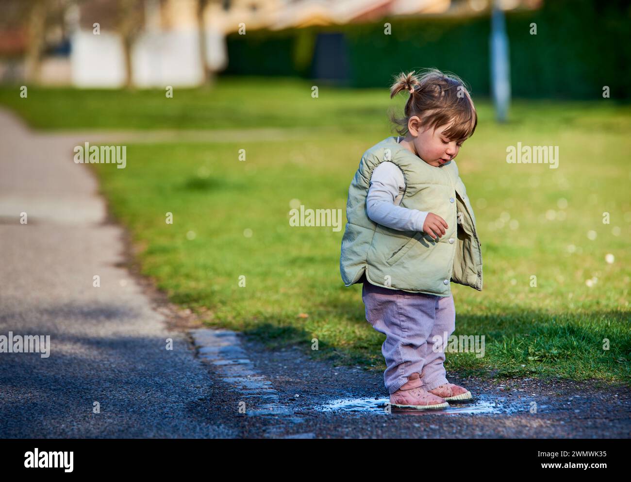 Rascal little female child with braids jumping in a muddy puddle on a ...