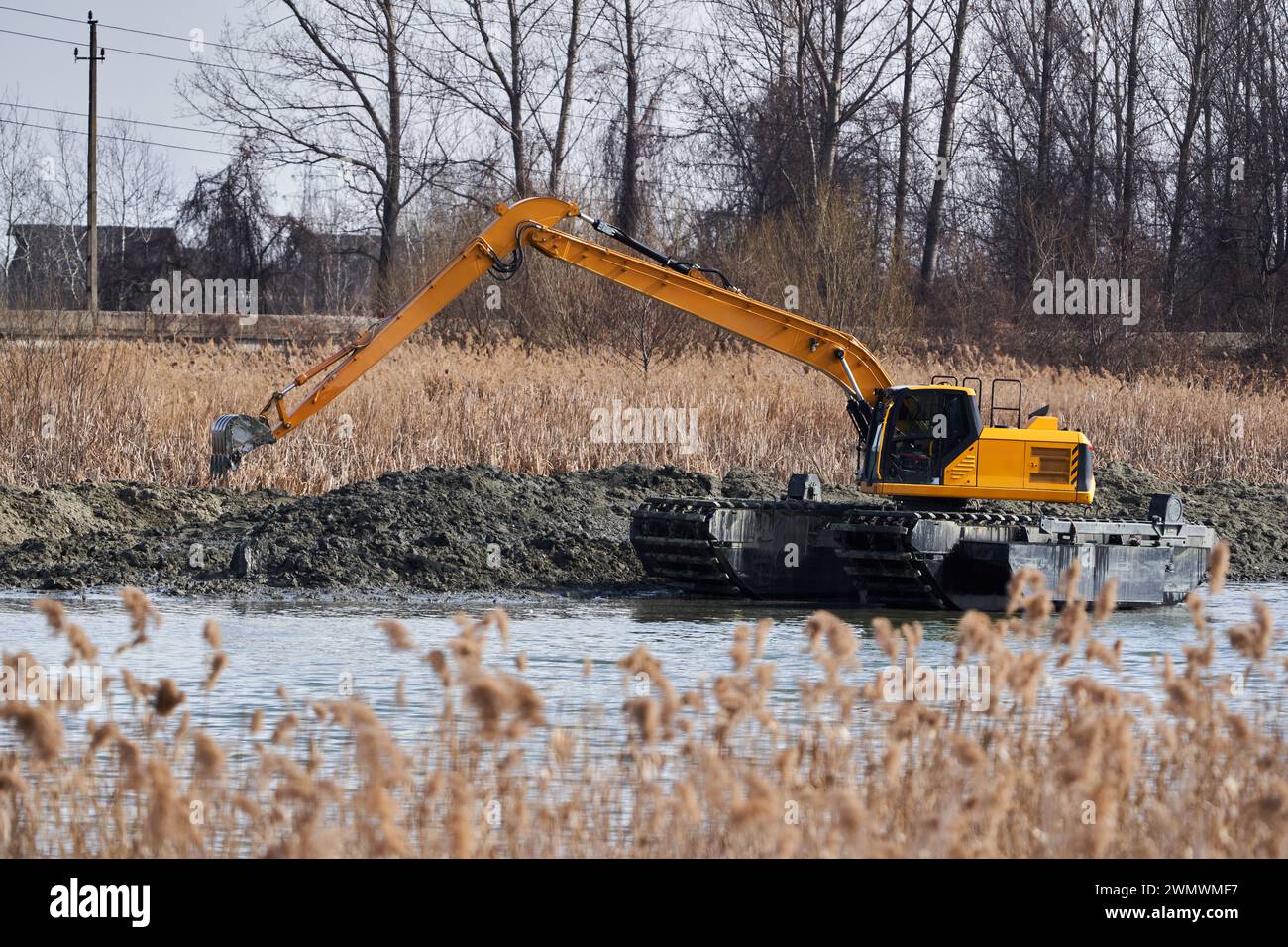 Earth digger, excavator, at the river's shore, working Stock Photo - Alamy
