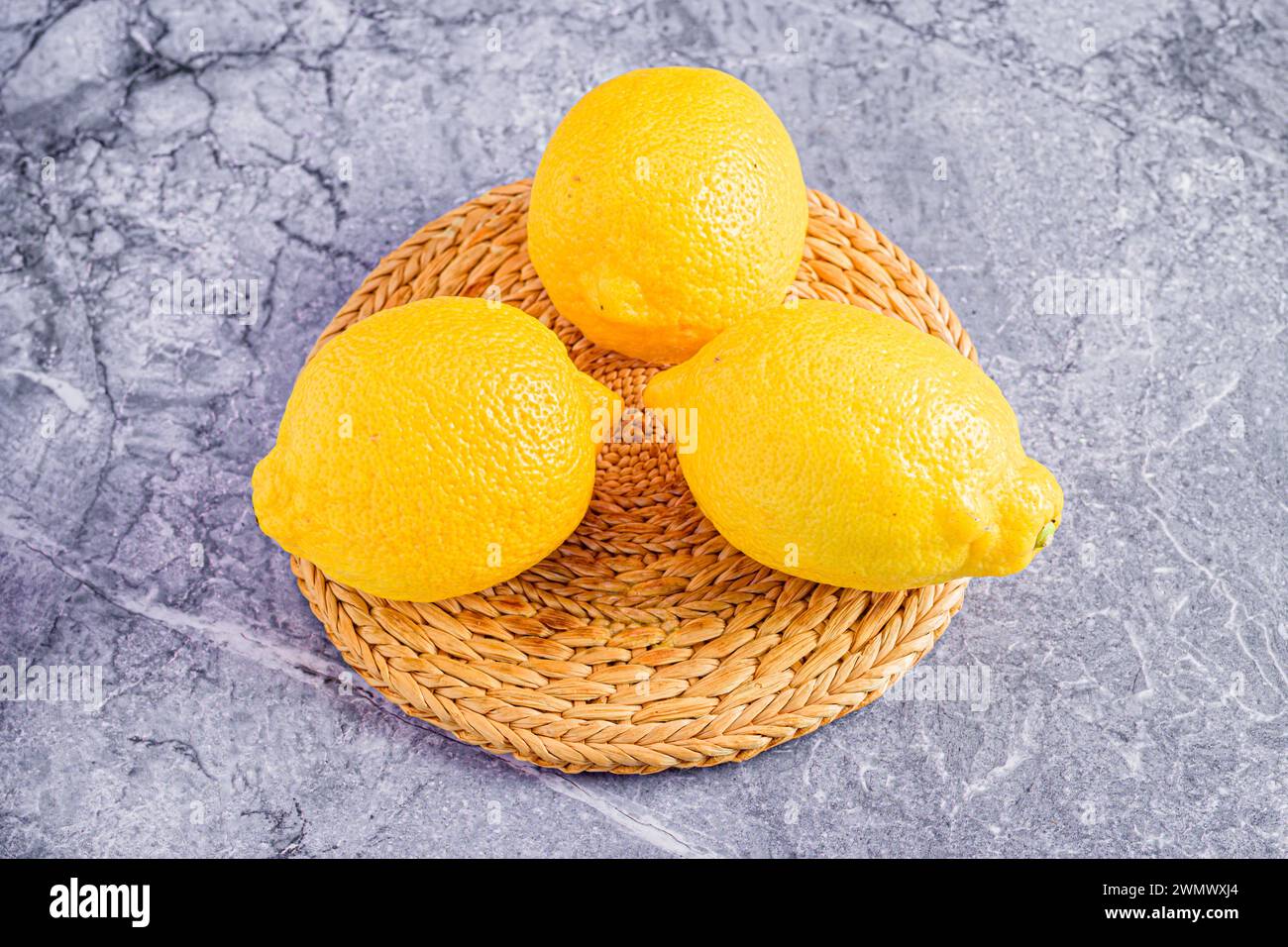 A Citrus Triangle: Lemons on Dark Marble and Circular Esparto Stock ...