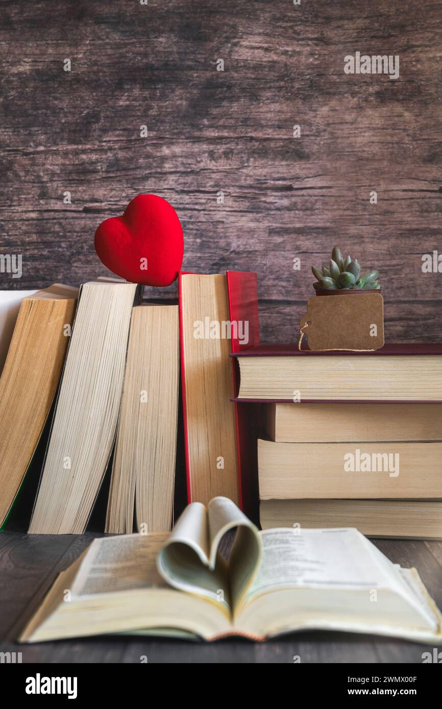 Open book, pages forming a heart, red heart on pile of books ...