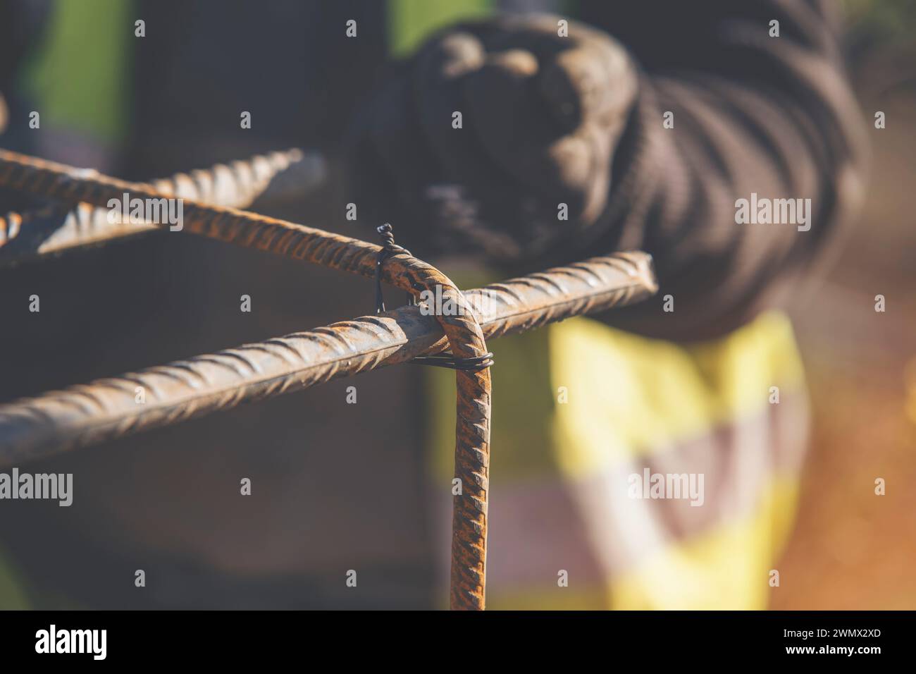 A worker uses steel tying wire to fasten steel rods to reinforcement ...