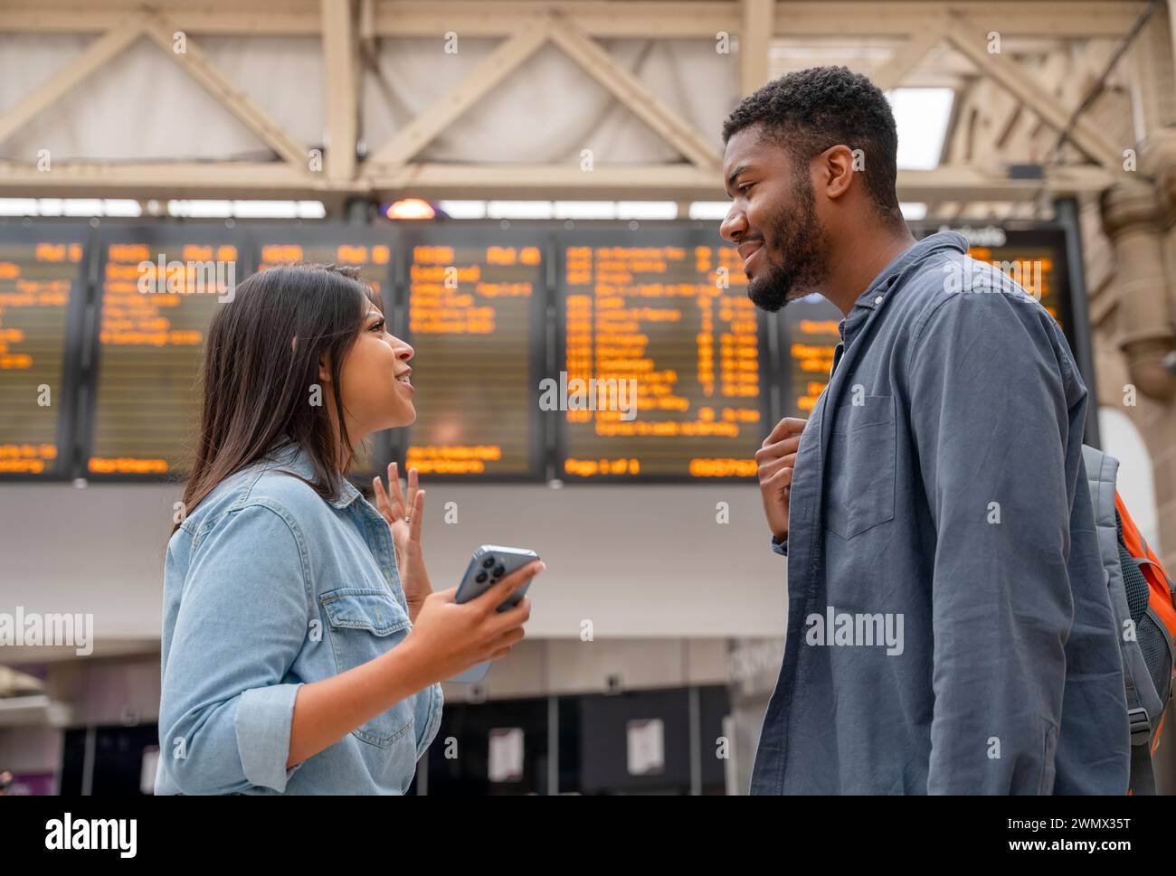 Group of multiracial friends checking time on departure board at a ...