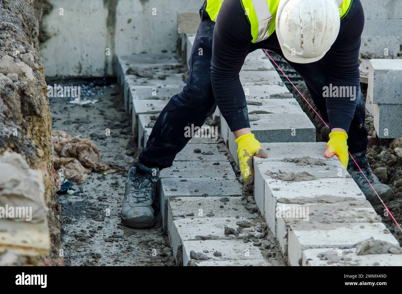 Hard working bricklayer laying concrete blocks on top of concrete ...