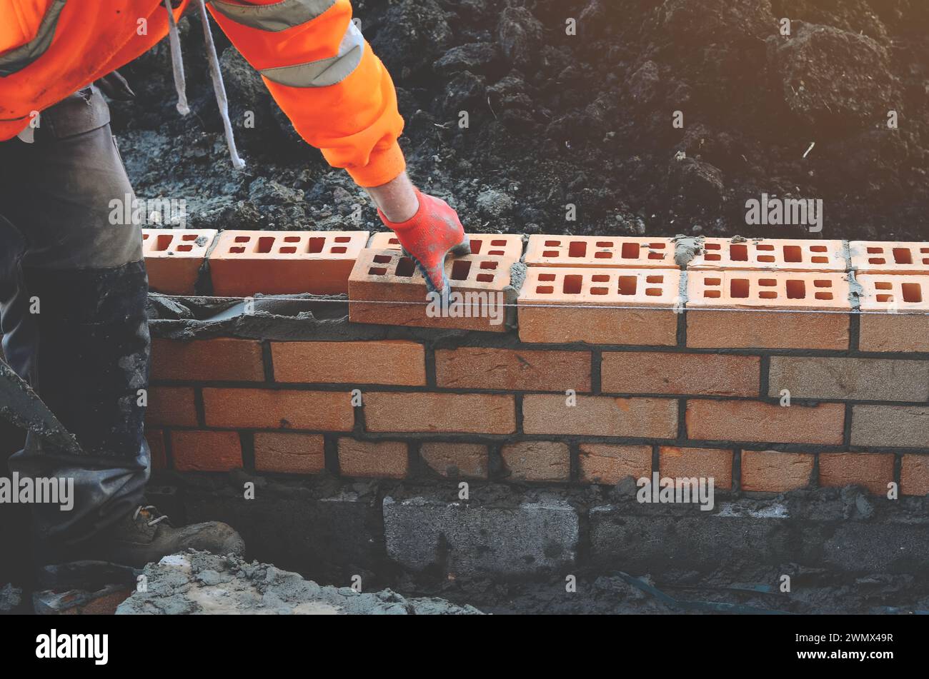 Industrial bricklayer laying bricks on cement mix on construction site ...