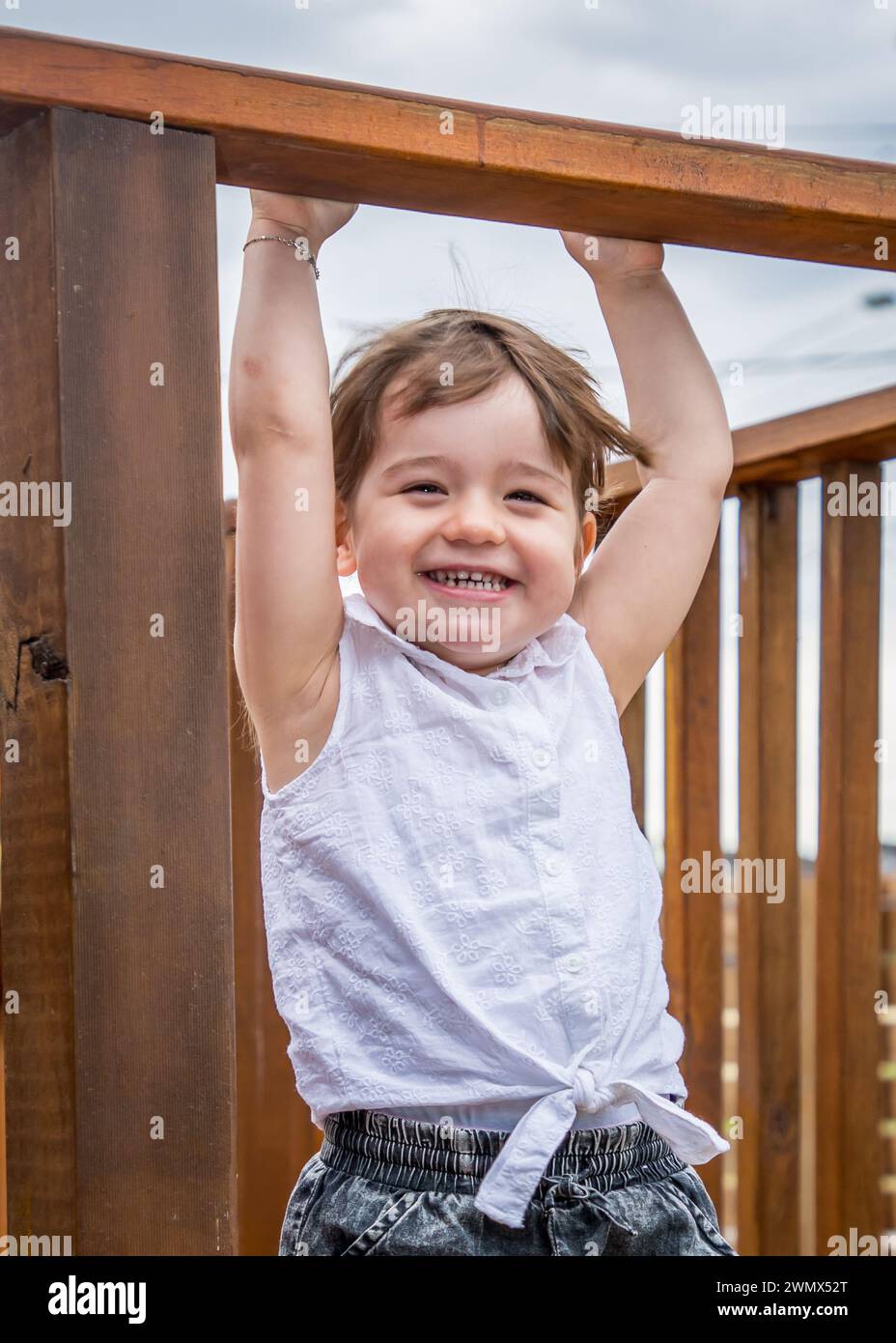 A young child hanging upside down on a wooden ledge alone Stock Photo - Alamy