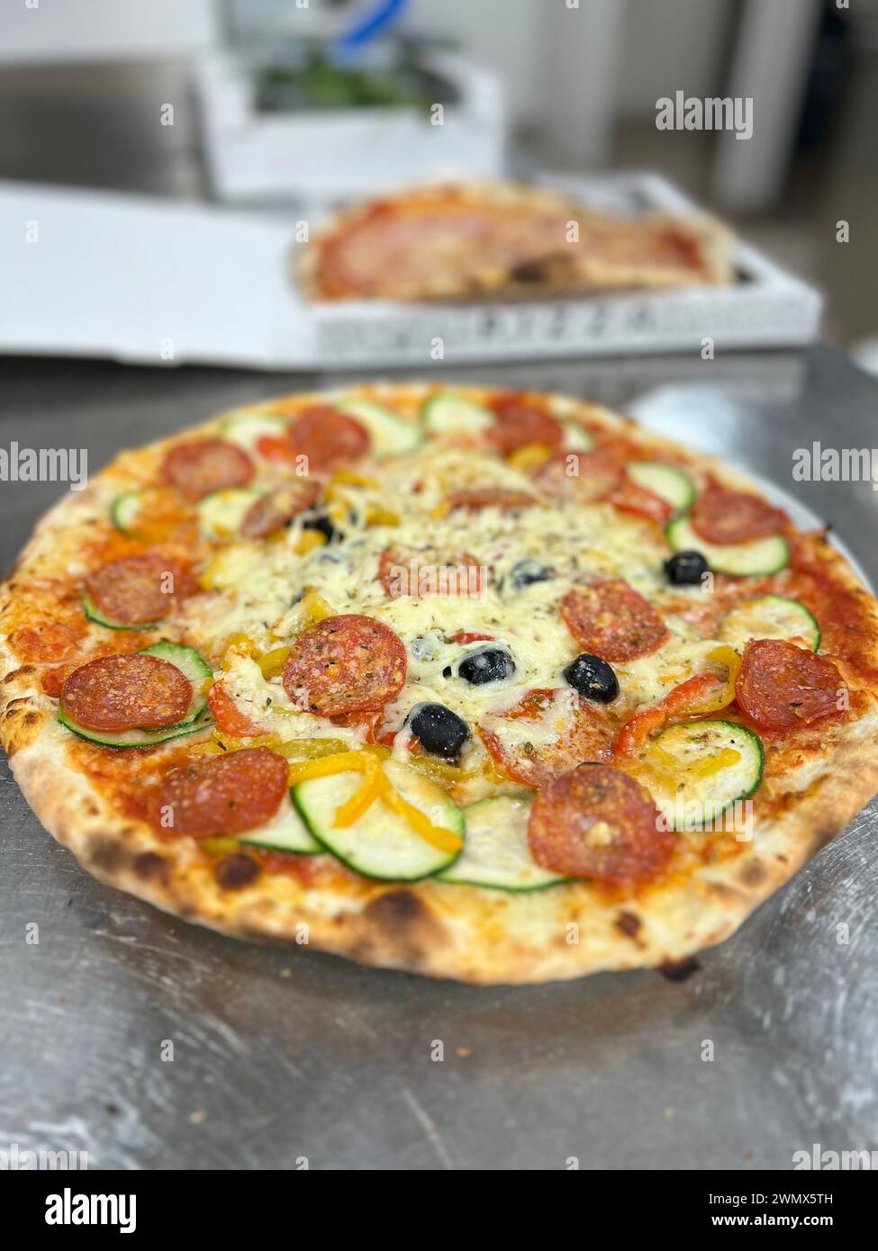 Freshly baked pizza in front of pizza boxes on a counter Stock Photo ...
