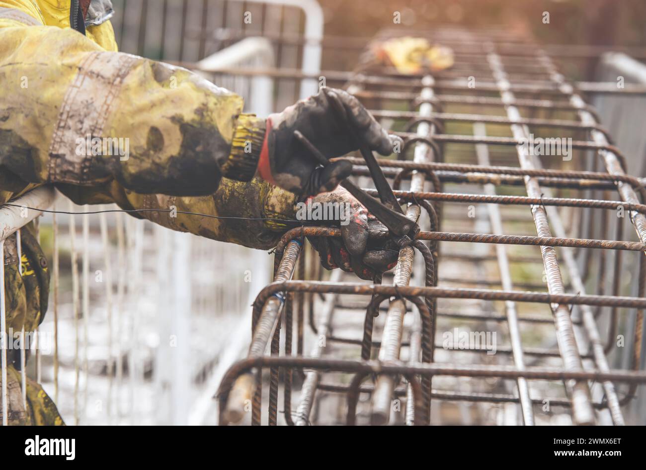 A worker uses steel tying wire to fasten steel rods to reinforcement ...