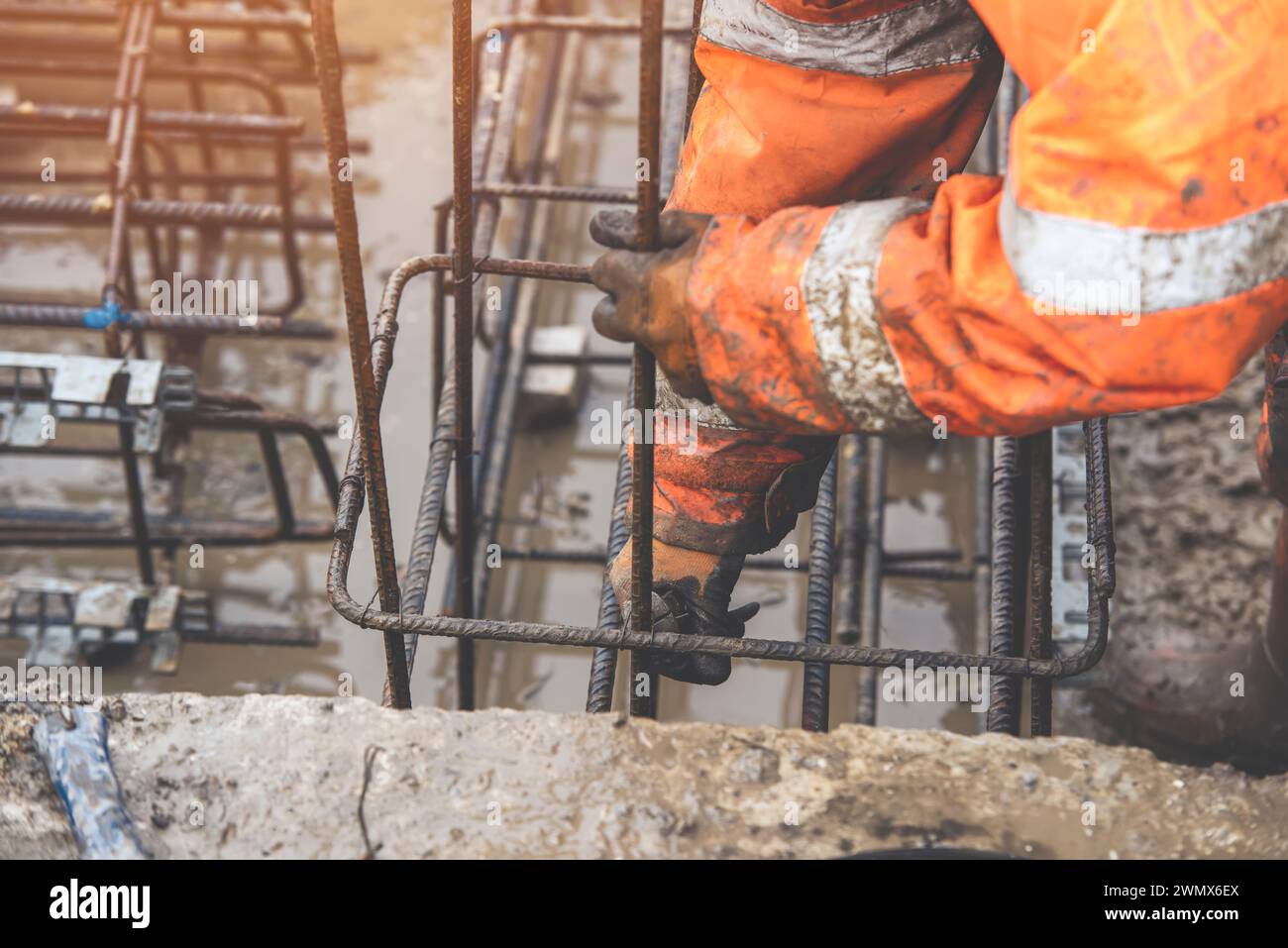 A worker uses steel tying wire to fasten steel rods to reinforcement ...