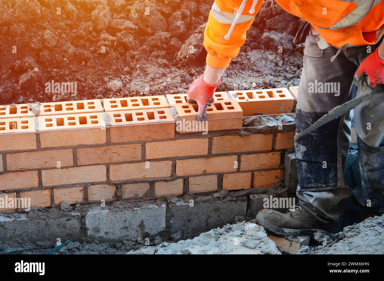 Industrial bricklayer laying bricks on cement mix on construction site ...