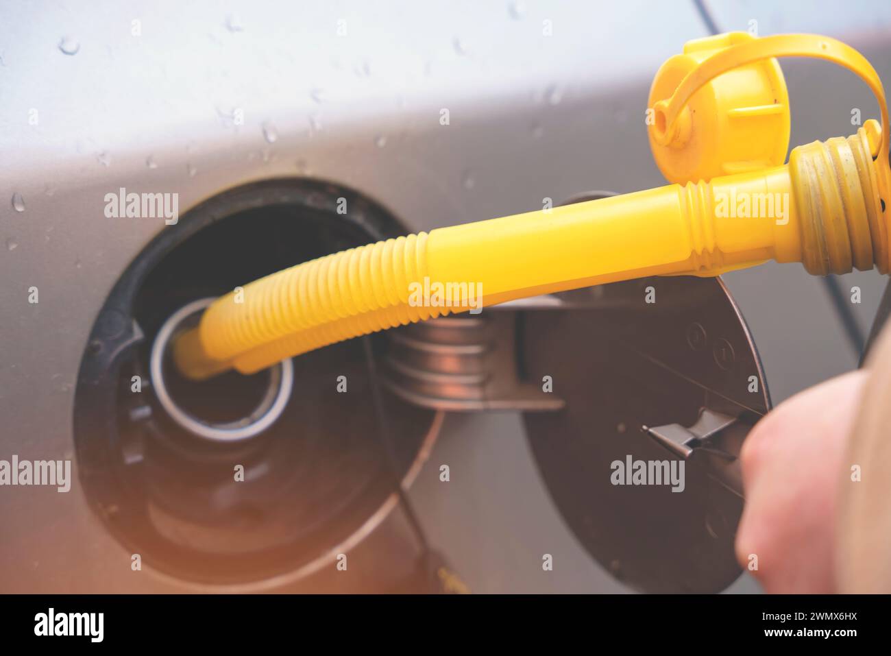 A man filling fuel tank of his car with diesel fuel from the jerry can ...