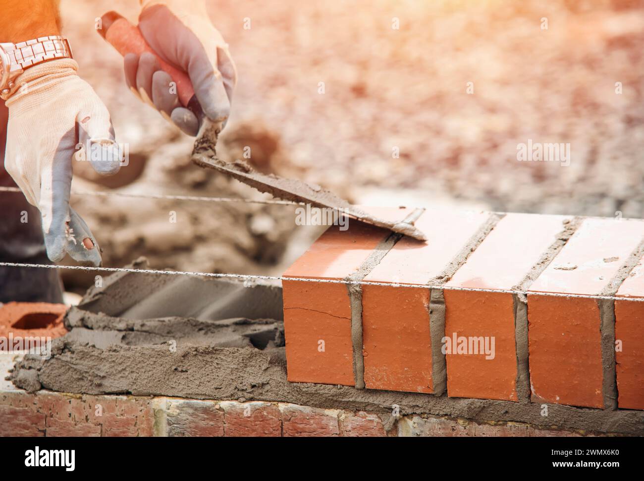 Industrial bricklayer laying bricks on cement mix on construction site ...