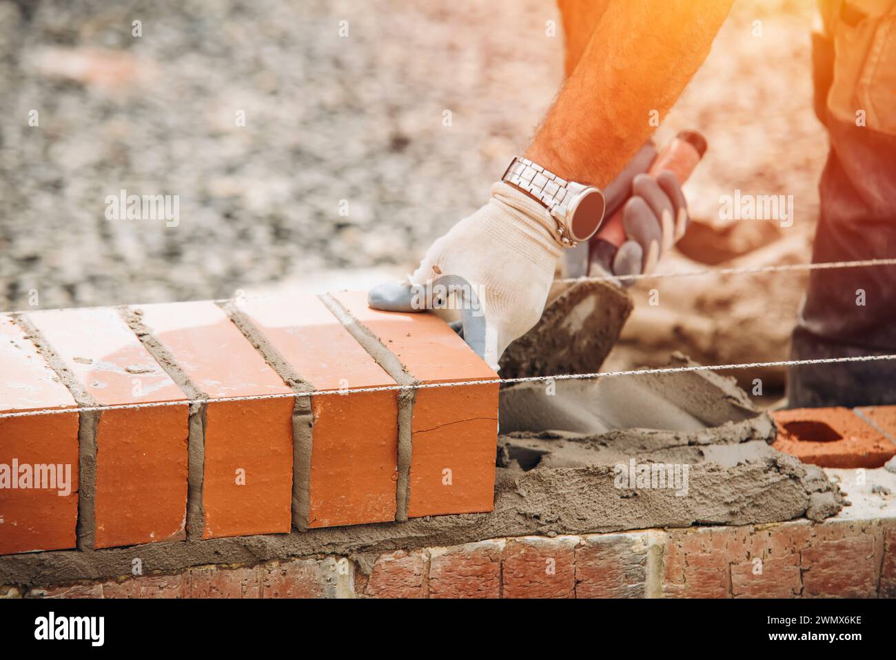 Industrial bricklayer laying bricks on cement mix on construction site ...