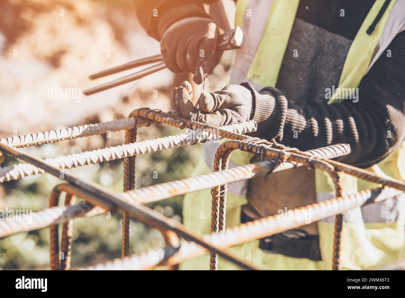 A worker uses steel tying wire to fasten steel rods to reinforcement ...
