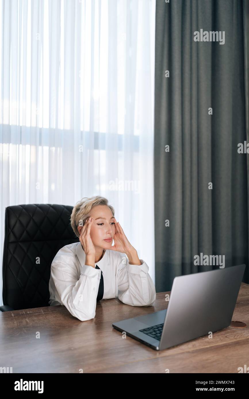 Vertical Portrait Of Tired Middle Aged Business Woman Using Laptop