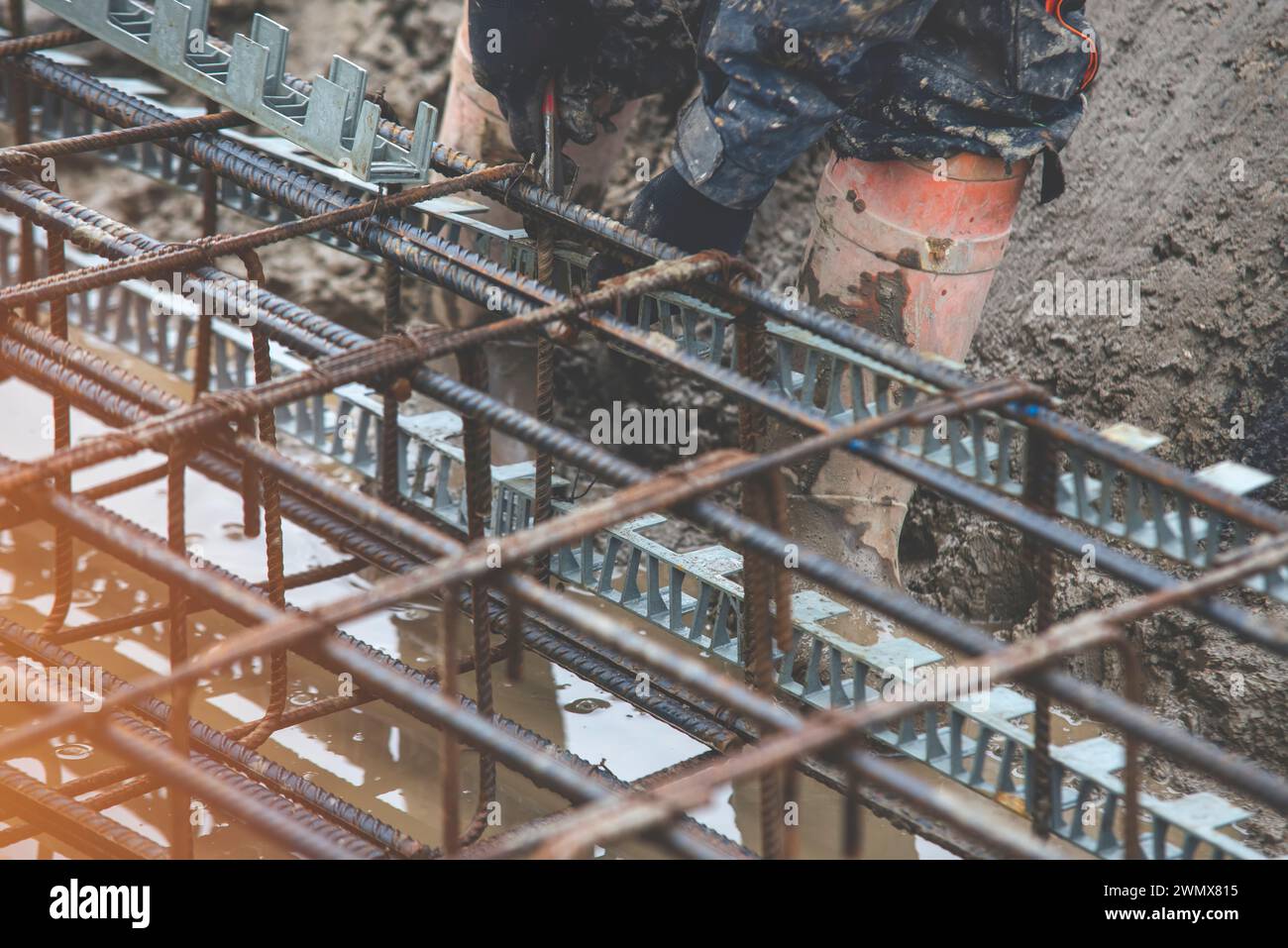 A worker uses steel tying wire to fasten steel rods to reinforcement ...