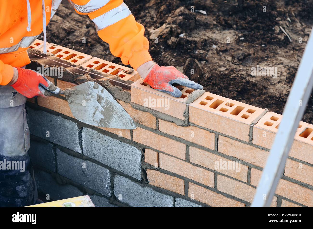 Industrial bricklayer laying bricks on cement mix on construction site ...