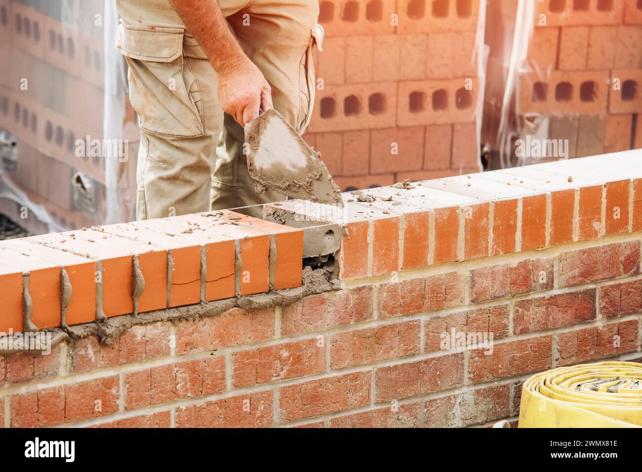 Industrial bricklayer laying bricks on cement mix on construction site ...