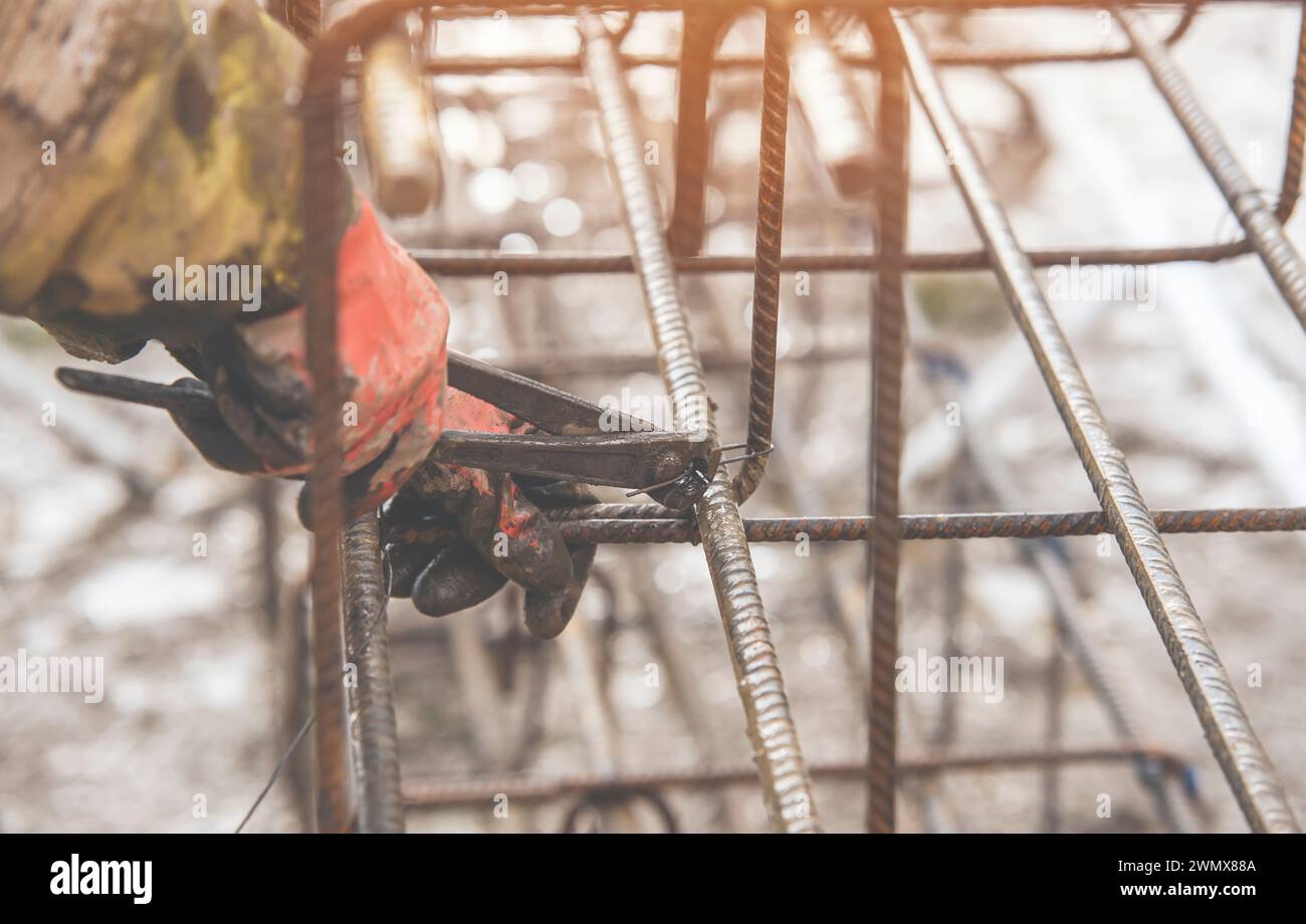 A worker uses steel tying wire to fasten steel rods to reinforcement ...