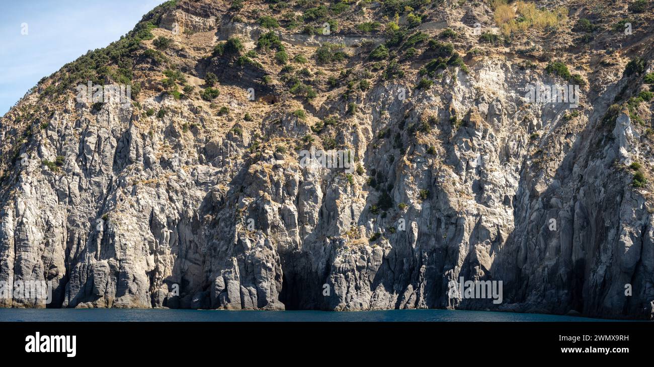 Weathered seaside rock face texture with parts of green and blue water ...