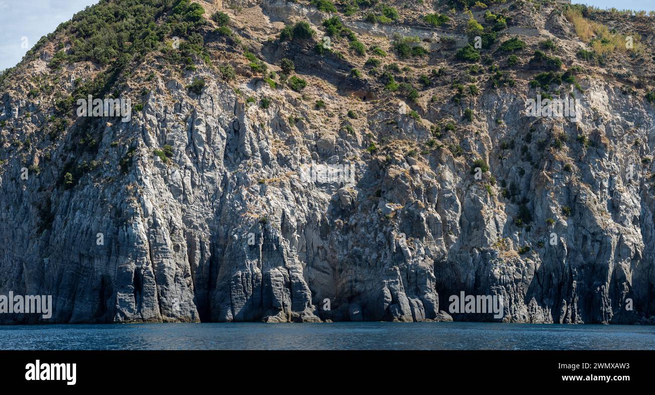 Weathered seaside rock face texture with parts of green and blue water ...