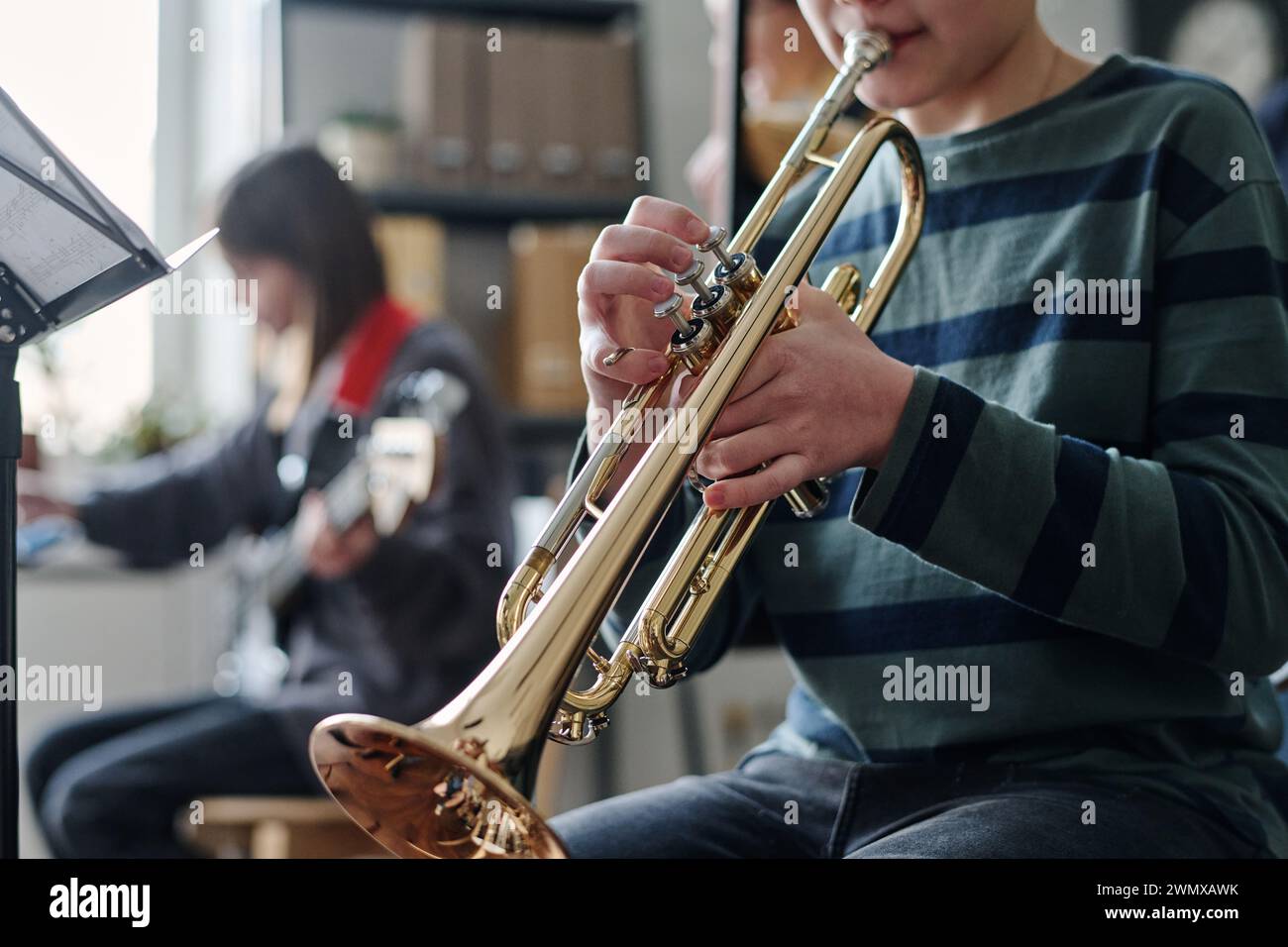Medium section shot of unrecognizable boy playing trumpet during school ...