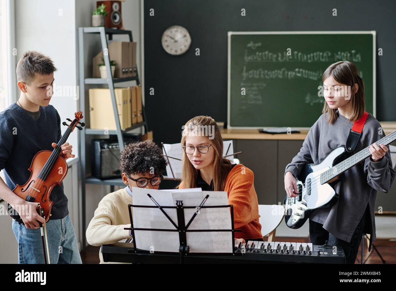 Medium long shot of young music teacher explaining her students how to ...
