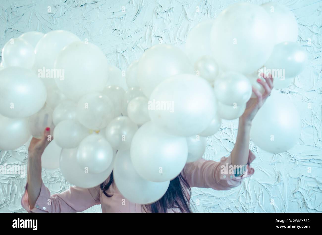 A woman actively playing with a multitude of white balloons fills the ...