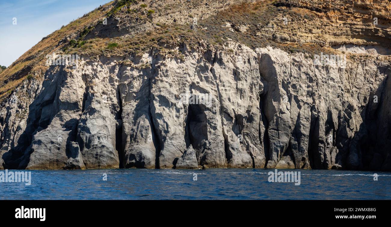 Weathered seaside rock face texture with parts of green and blue water ...