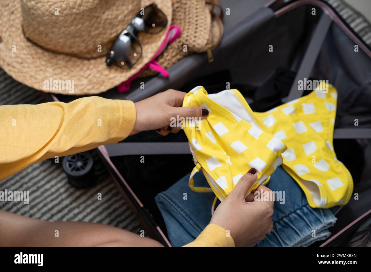 A young woman is packing a suitcase, getting ready to travel on a well ...