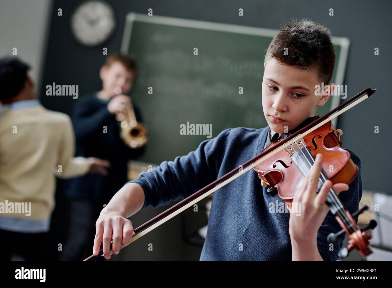 Selective focus dutch angle shot of modern teen boy playing violin ...