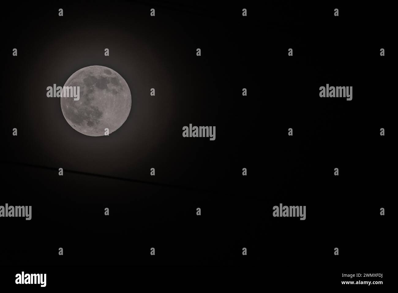 June full moon surrounded by a halo caused by gases in the atmosphere ...