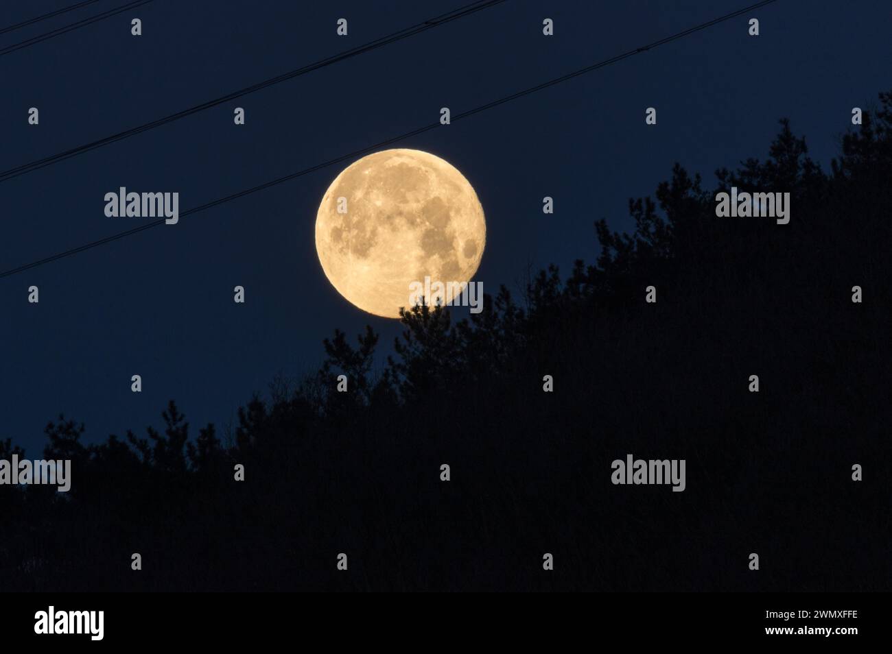 February full moon just above the side of a mountain as it sets in the ...