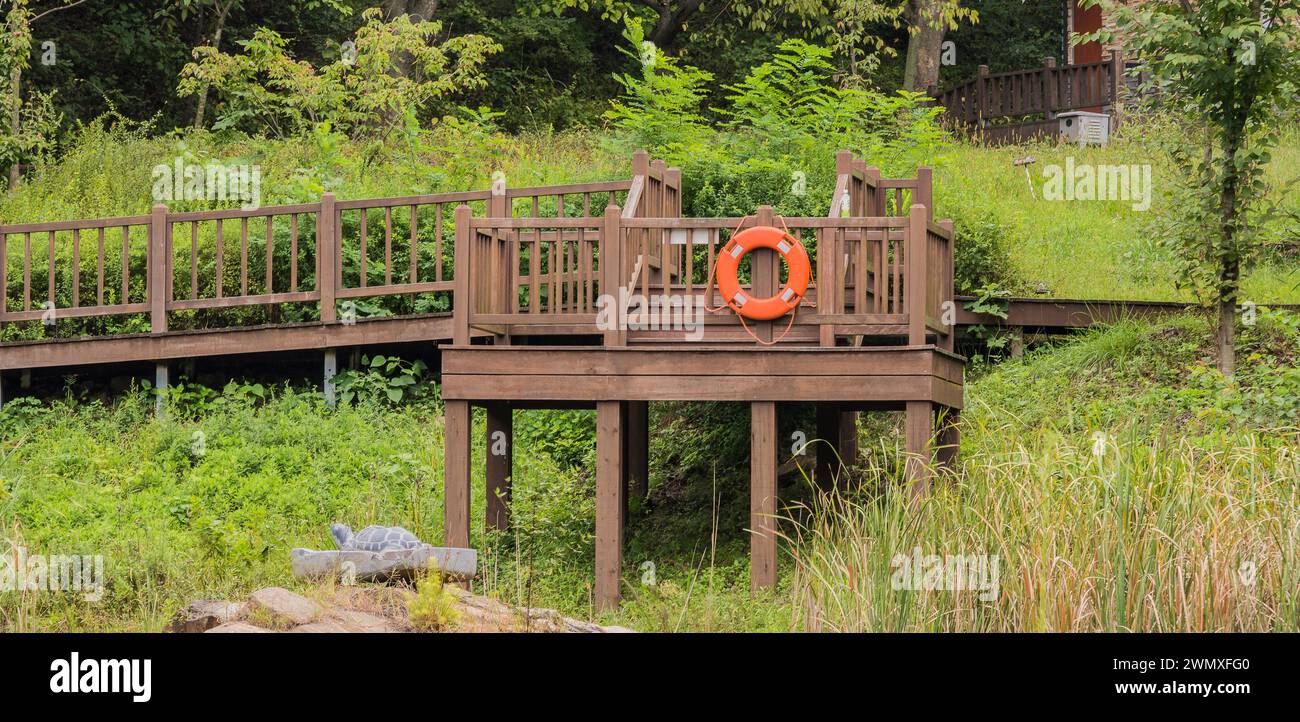 Wooden observation deck with a lifebuoy overlooking a natural area, in ...