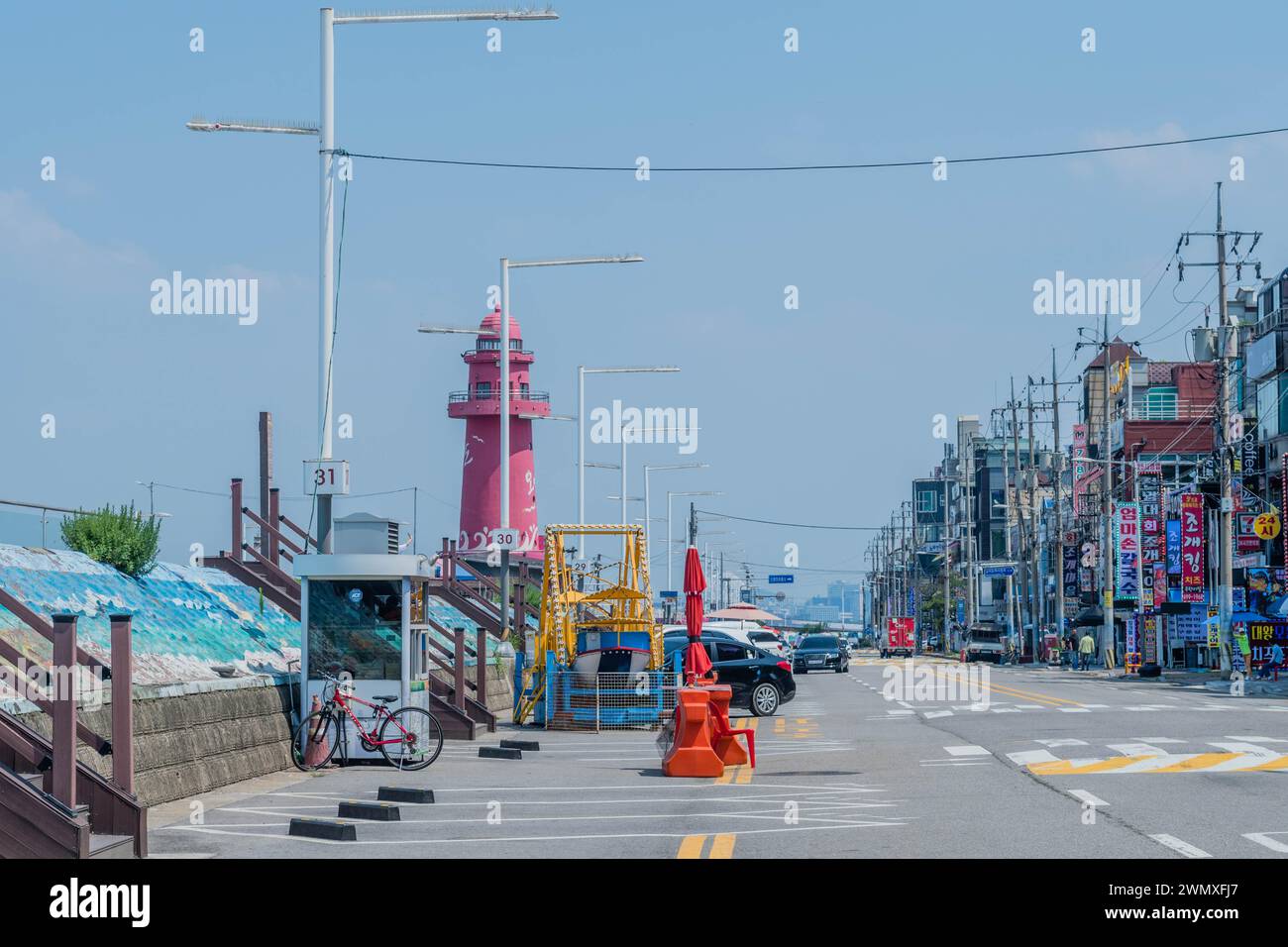 Oido red lighthouse on pier beside main street lined with businesses in ...
