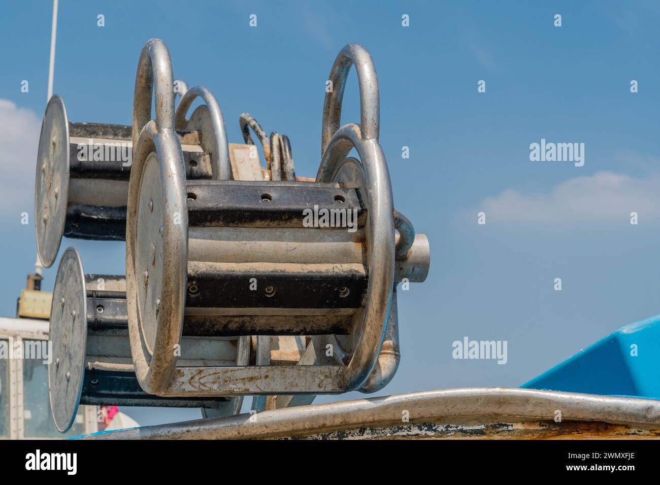 Closeup of netting spool mechanism on small fishing trawler with blue ...
