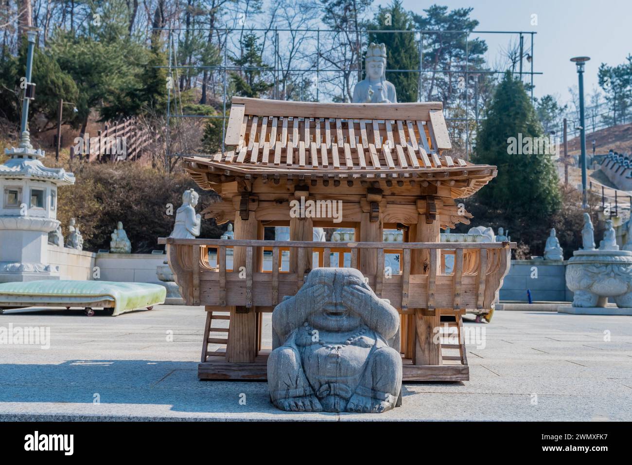 Sitting Buddha with hands over eyes in front of miniature wooden ...